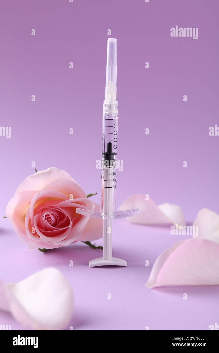 Cosmetology. Medical syringe, rose flower and petals on pink background ...