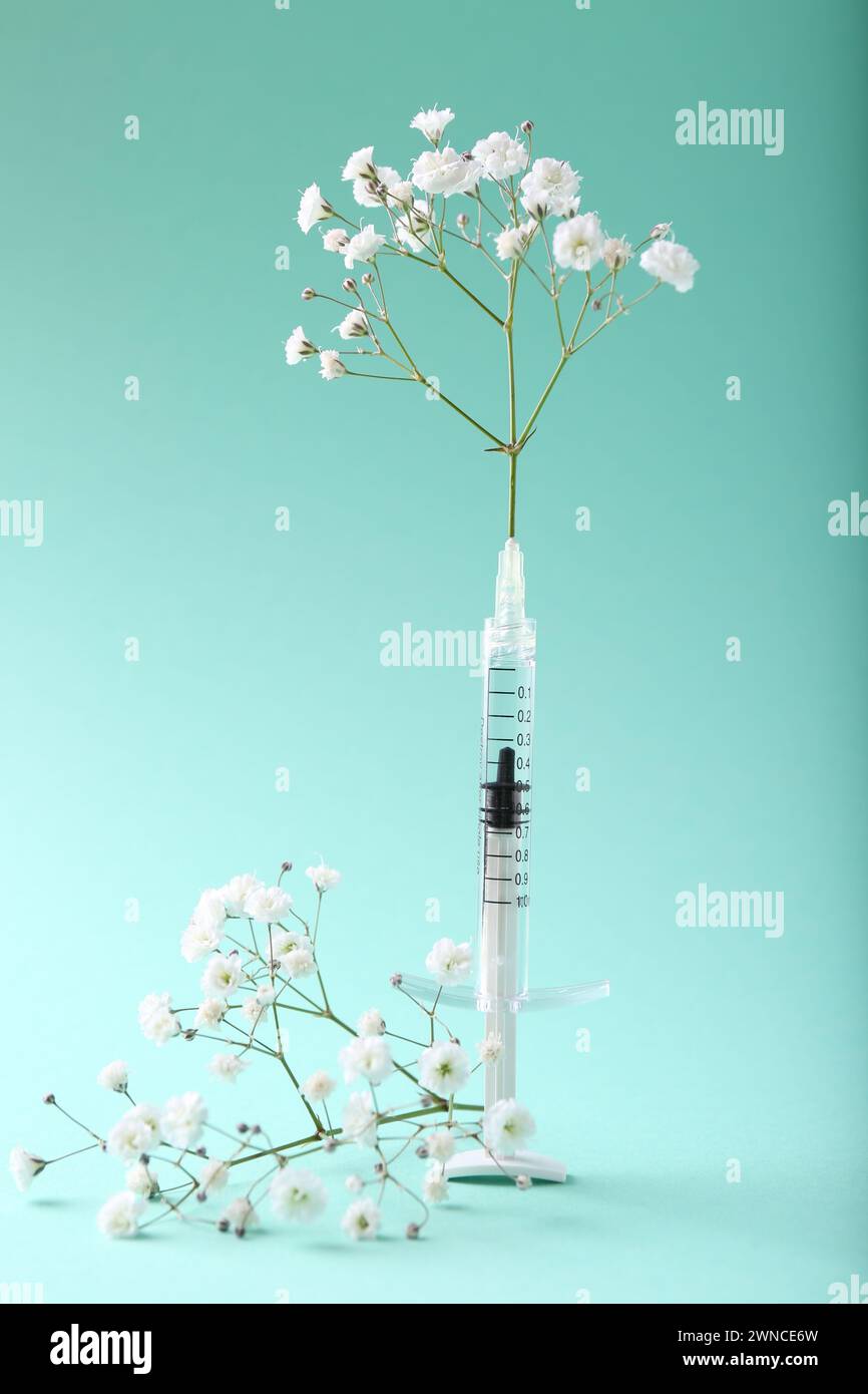 Cosmetology. Medical syringe and gypsophila flowers on turquoise ...