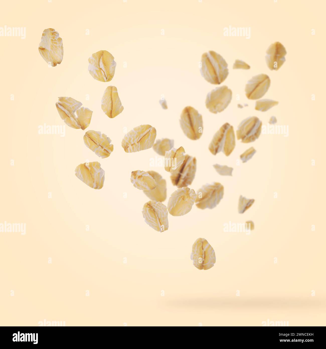Rolled oat flakes falling on beige background Stock Photo - Alamy