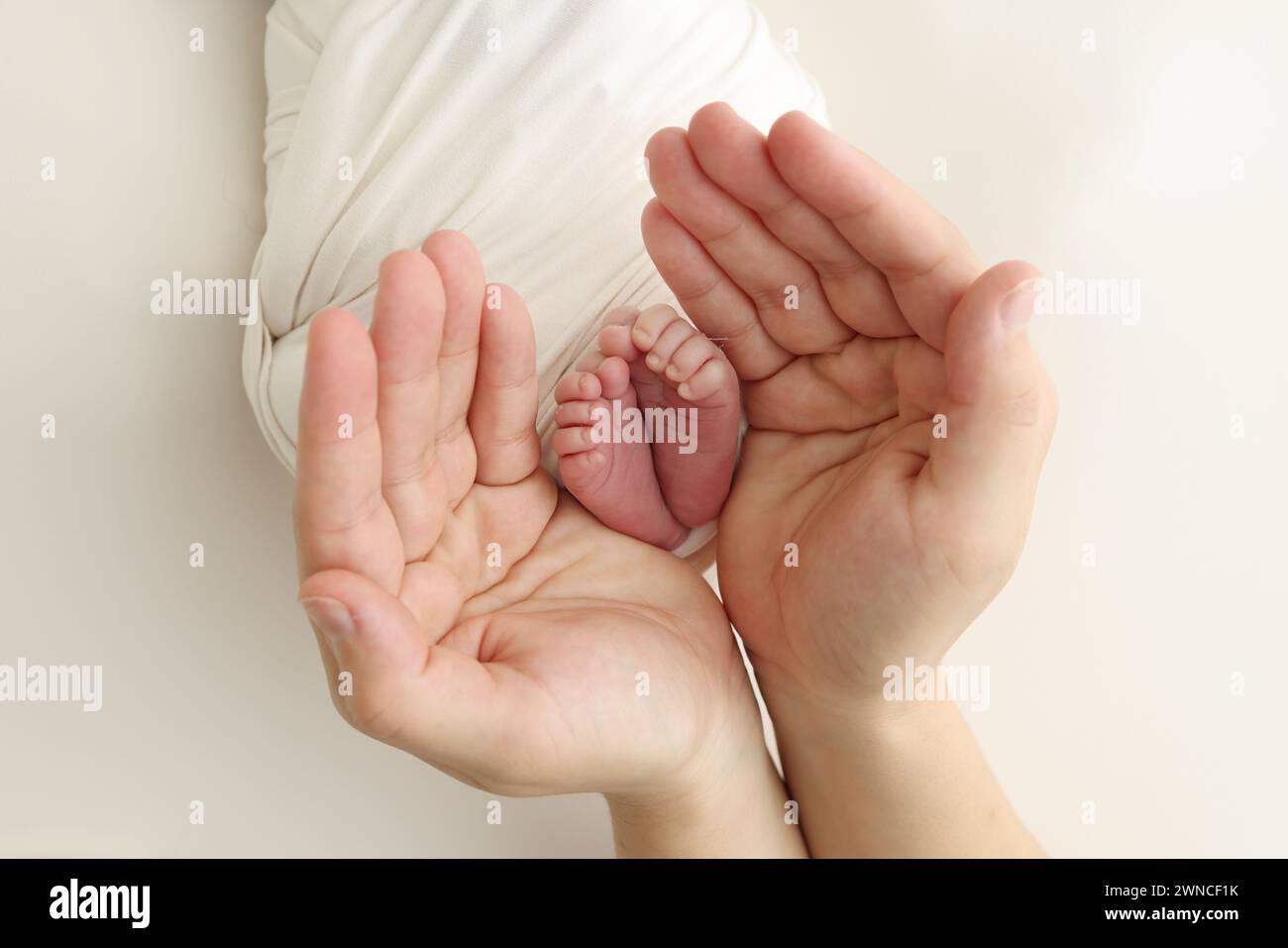 The palms of the father, the mother are holding the foot of the newborn ...