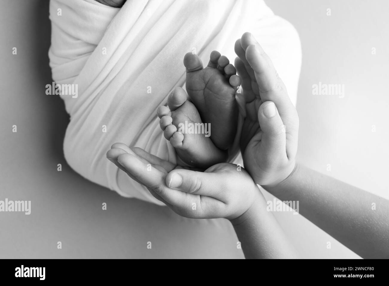 The palms of the father, the mother are holding the foot of the newborn ...