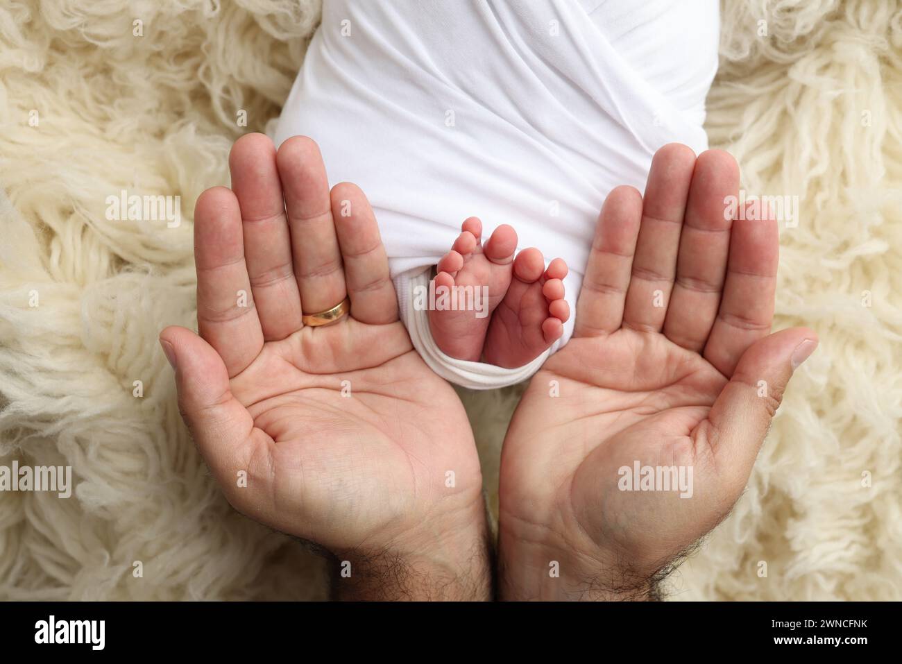 The palms of the father, the mother are holding the foot of the newborn ...