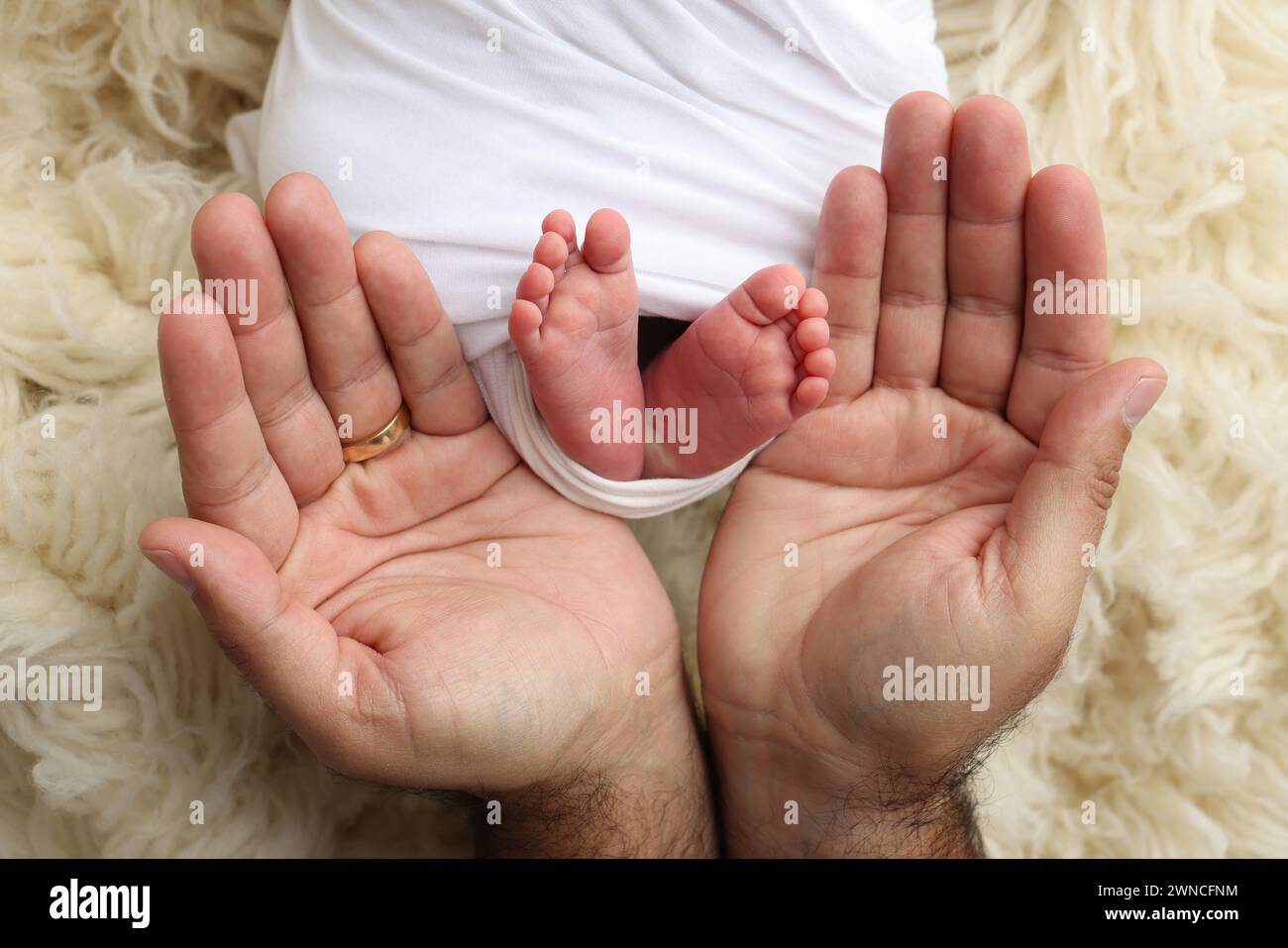 The palms of the father, the mother are holding the foot of the newborn ...