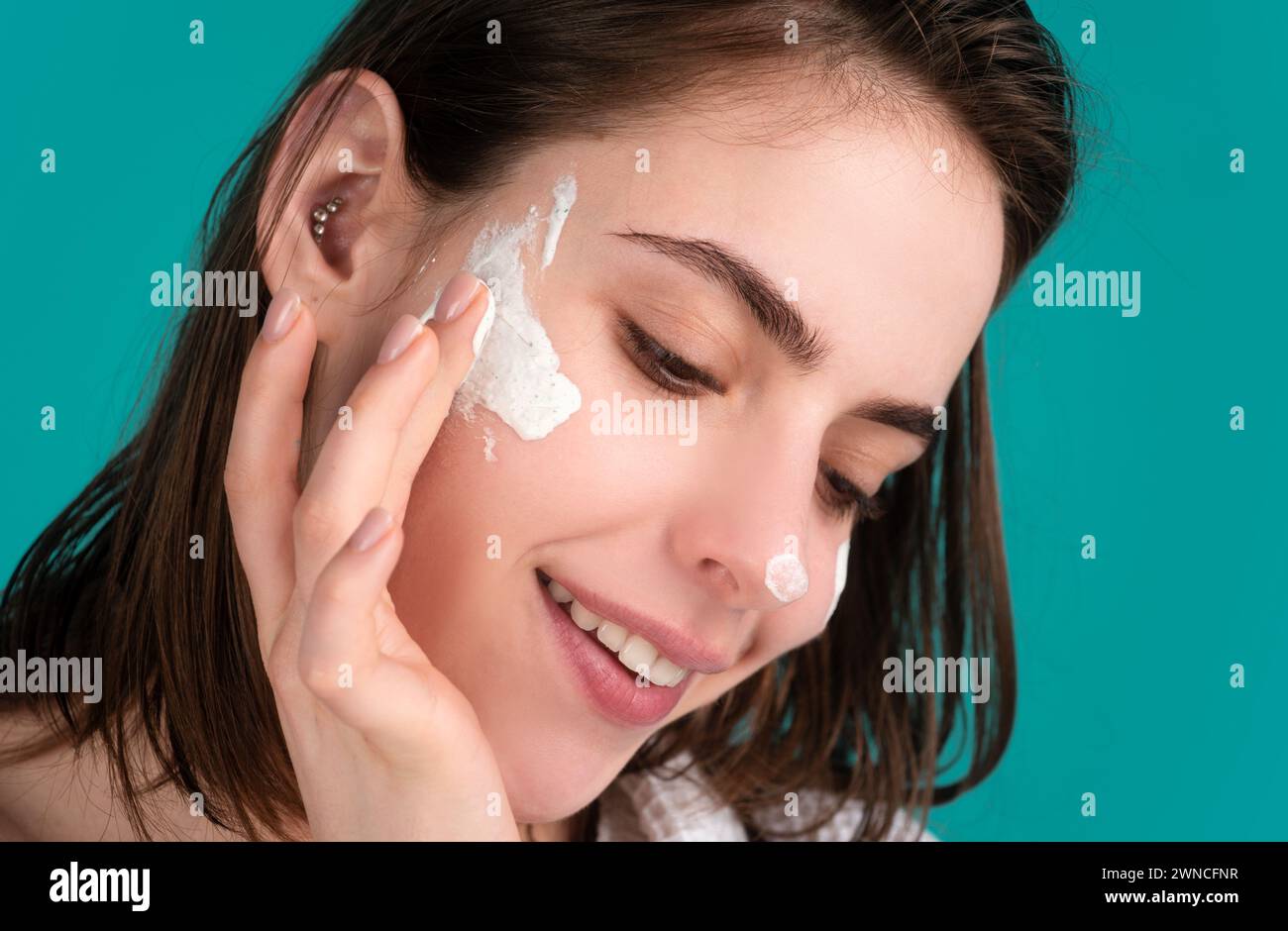 Beautiful girl model with natural makeup applying moisturizer cream on ...