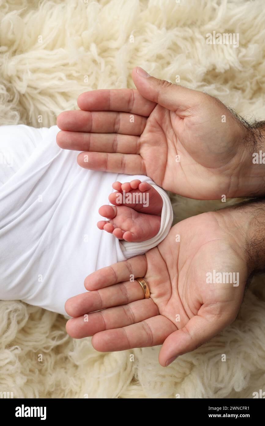 The palms of the father, the mother are holding the foot of the newborn ...
