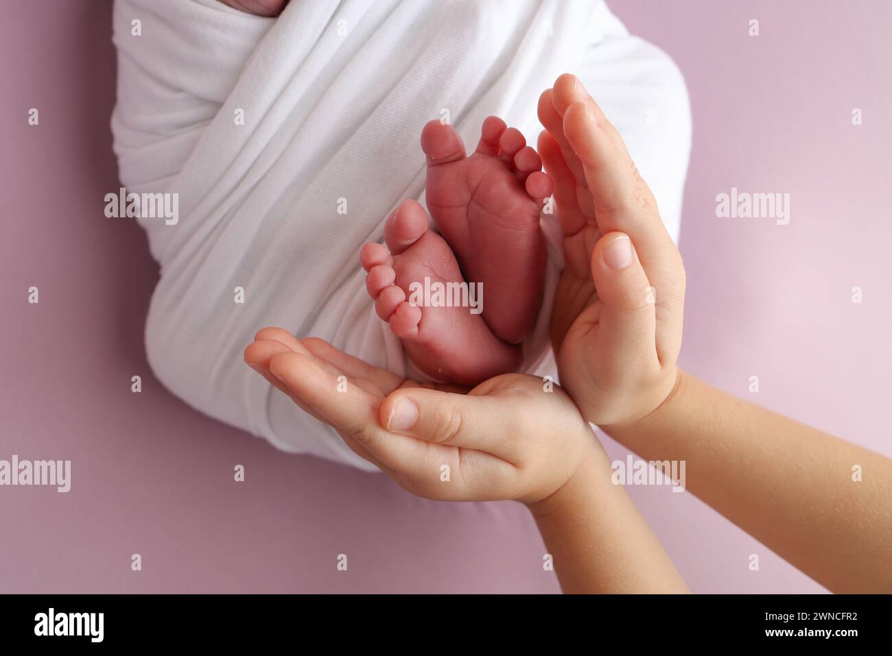 The palms of the father, the mother are holding the foot of the newborn ...