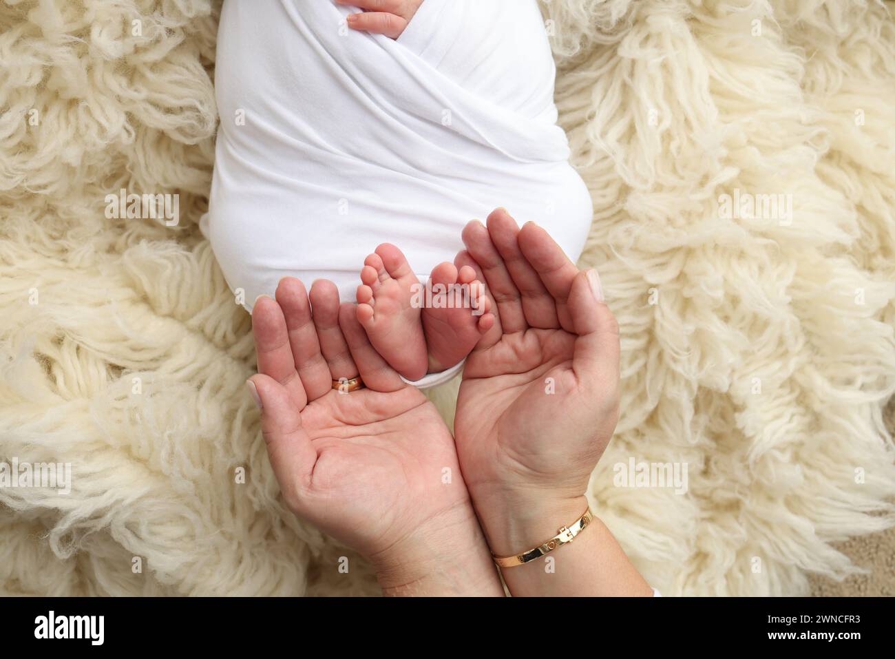 The palms of the father, the mother are holding the foot of the newborn ...