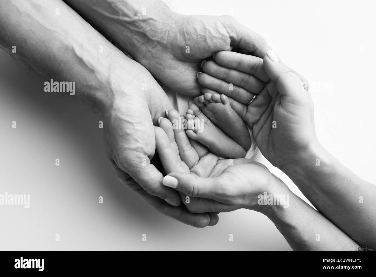 The palms of the father, the mother are holding the foot of the newborn ...