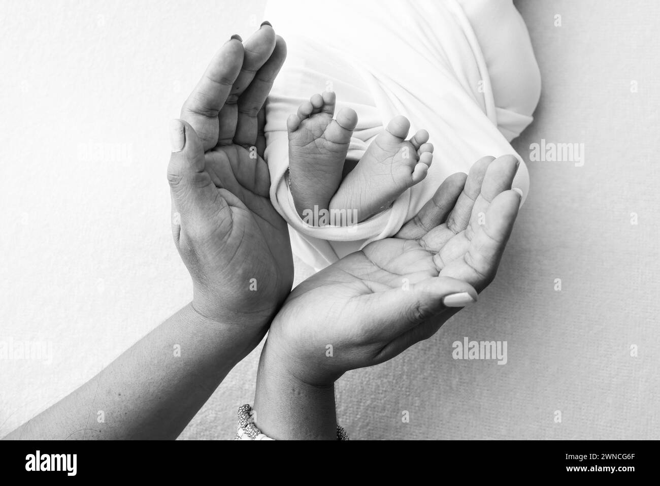 The palms of the father, the mother are holding the foot of the newborn ...