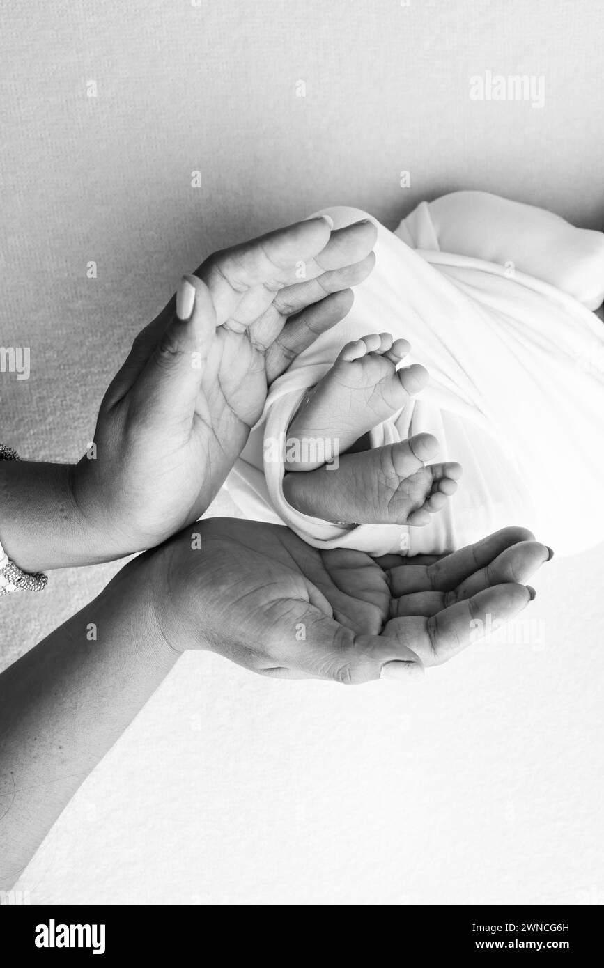 The palms of the father, the mother are holding the foot of the newborn ...