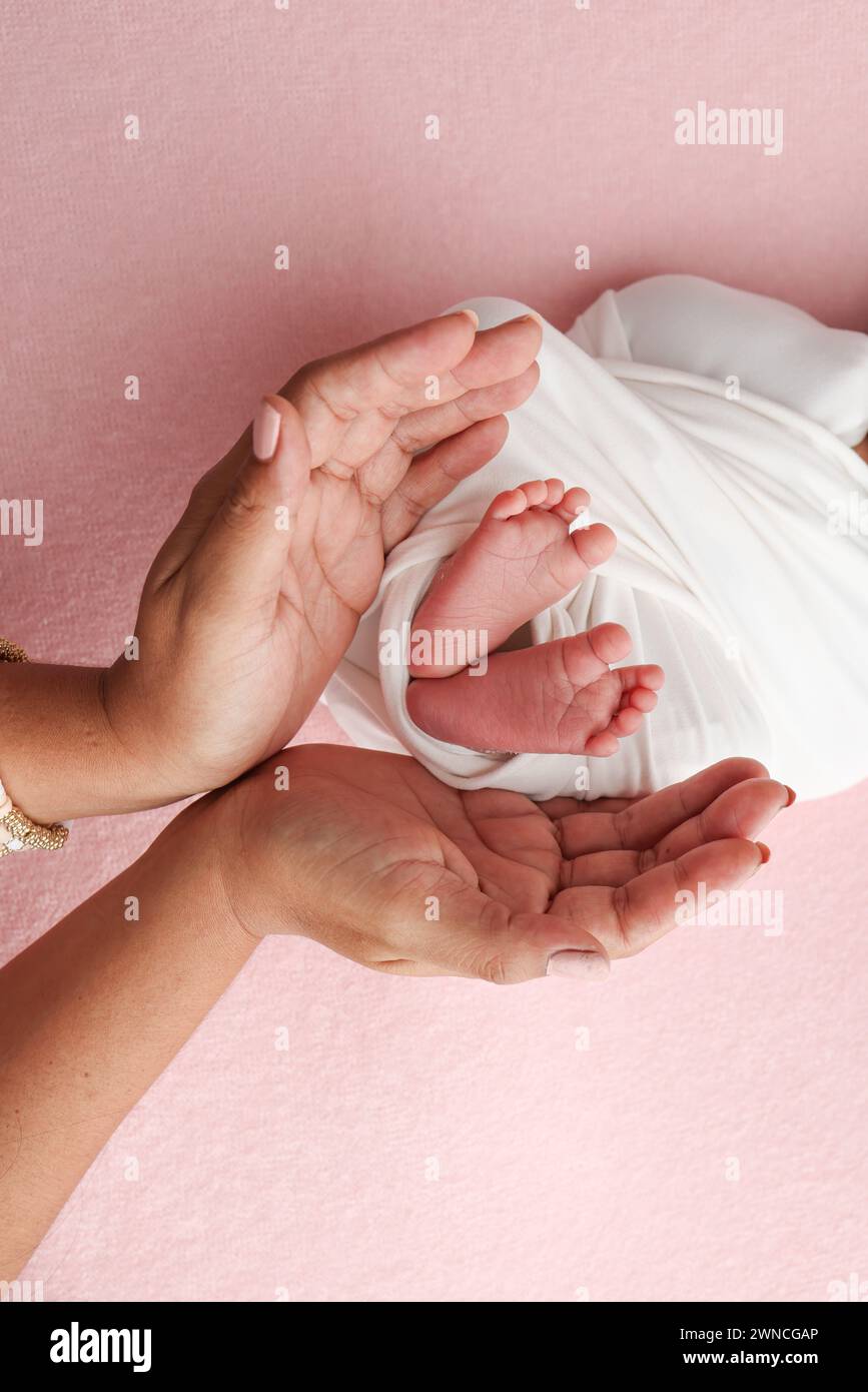 The palms of he mother are holding the foot of the newborn baby in a ...