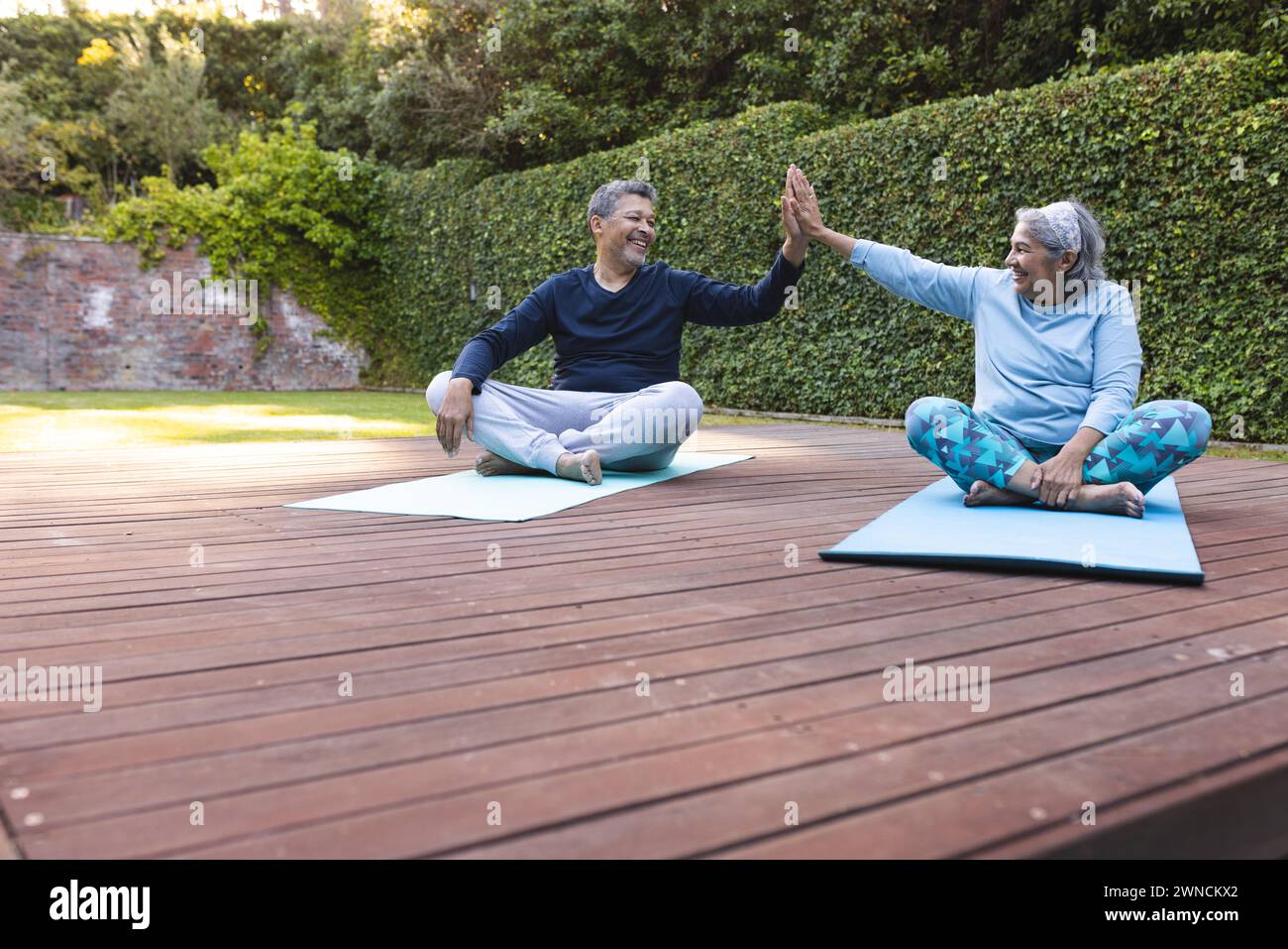 Senior biracial woman and biracial man share a high-five during a yoga ...
