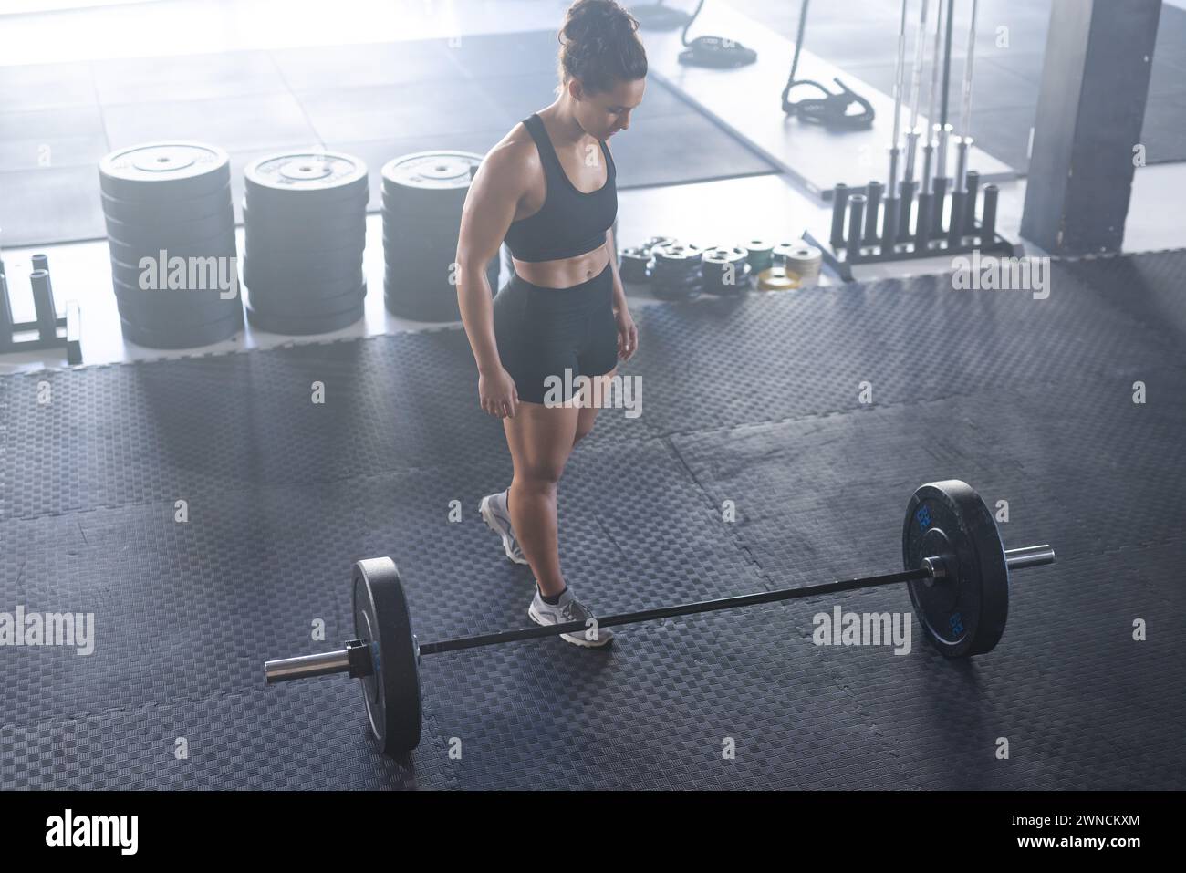 Young **fit** biracial woman prepares to lift a barbell at the gym ...