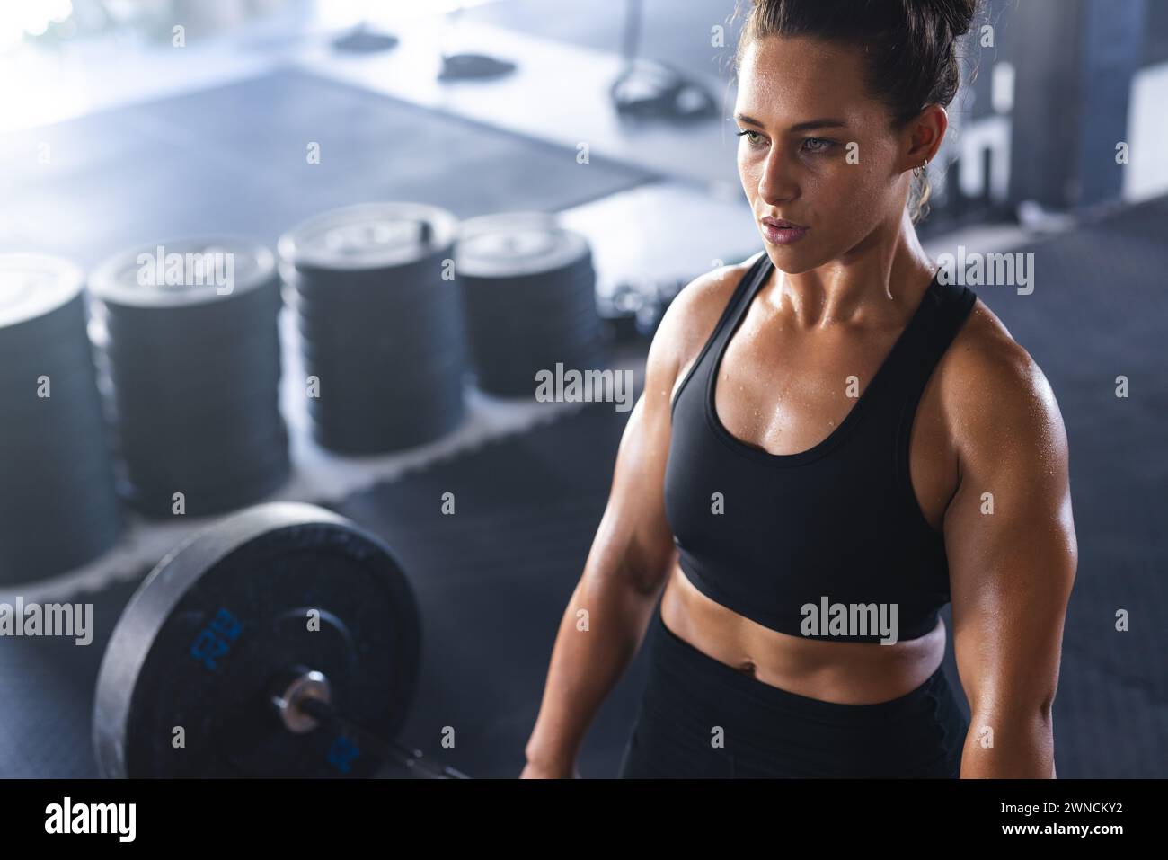 A young **strong** fit biracial woman prepares to lift a barbell at the ...