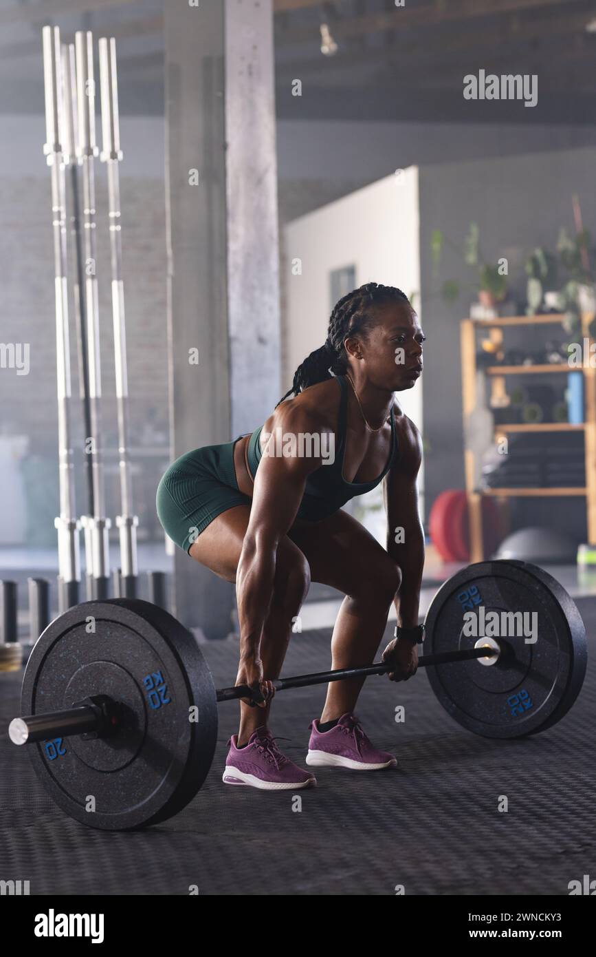 Strong biracial woman in her mid-30s performs a deadlift in a gym Stock ...