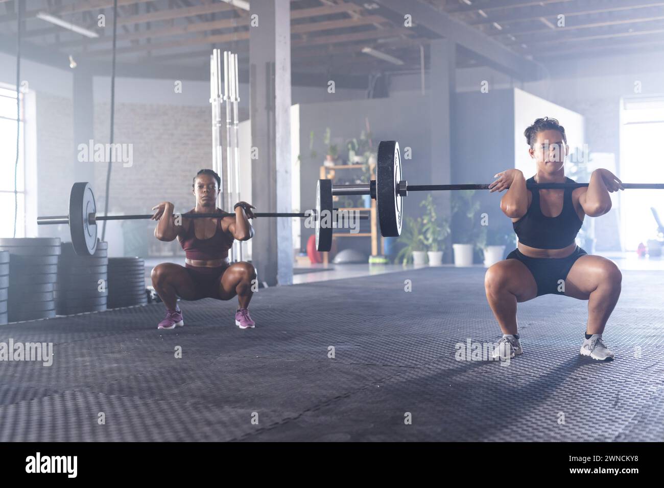Two women are lifting barbells in a gym, focused on their workout Stock ...