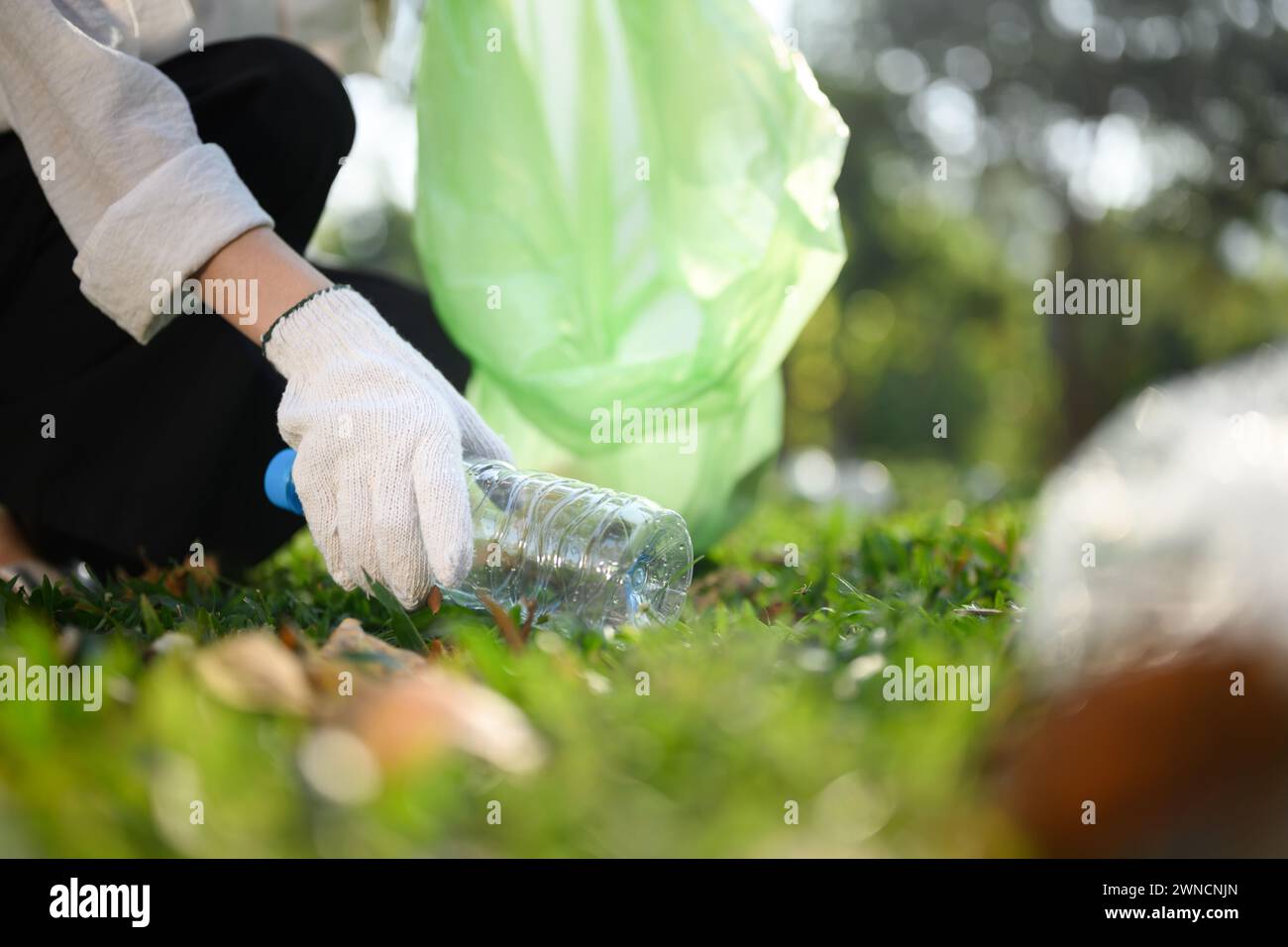 Closeup young woman hand collecting plastic bottles, cleaning up nature ...