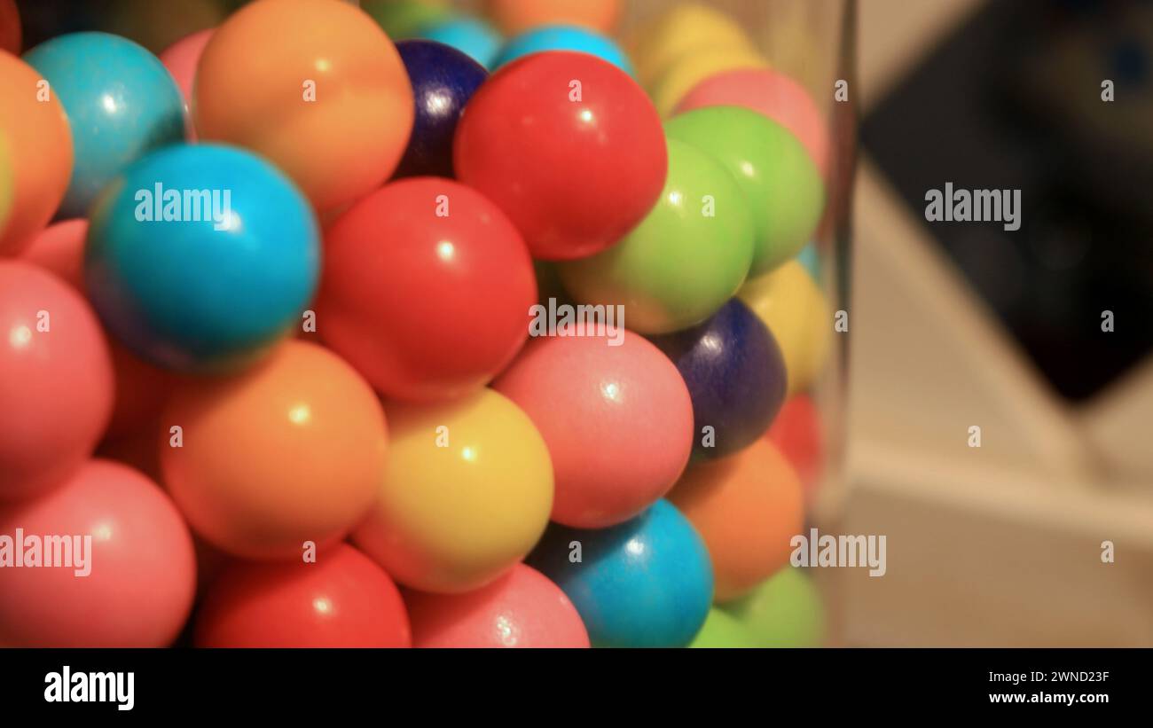 A close-up defocus photo of a jar filled with colorful sweets that look ...