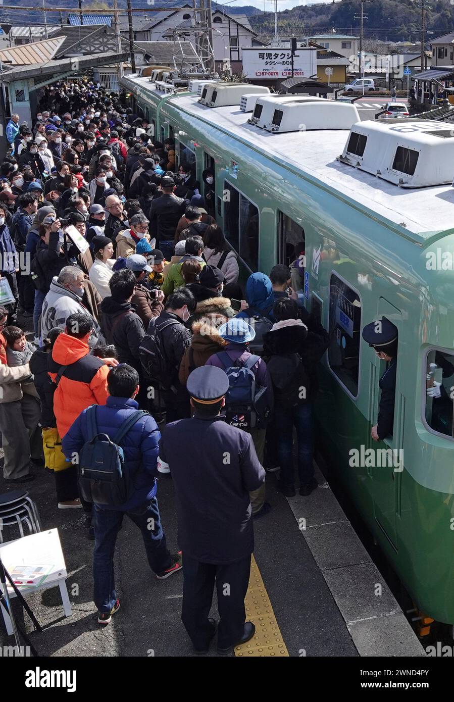 Trainspotters crowd the Mitake Station to see a reprint painting train ...