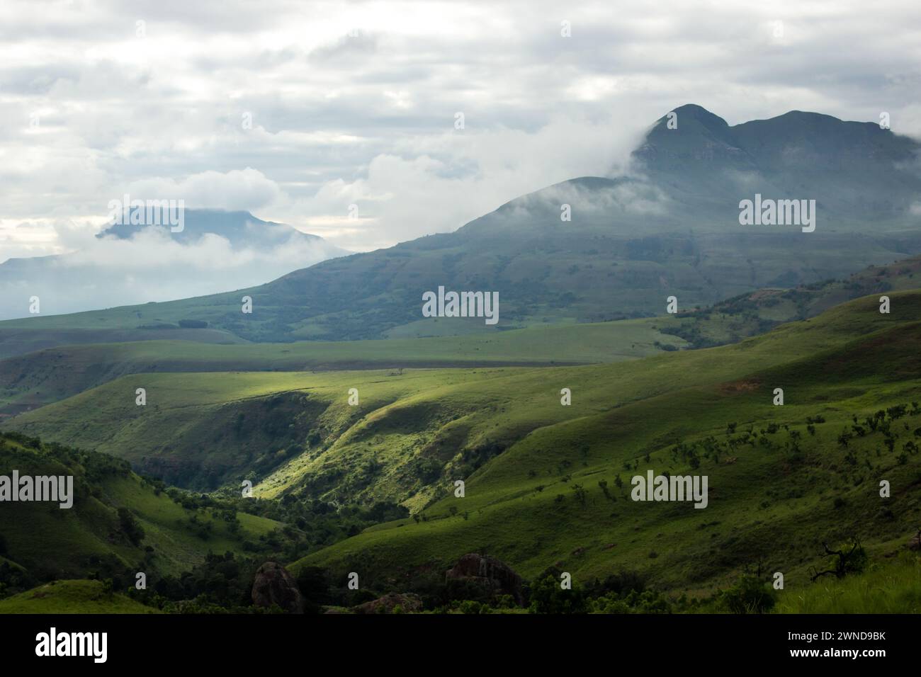 Green sunlit valley, with the mountains in the background shrouded in ...