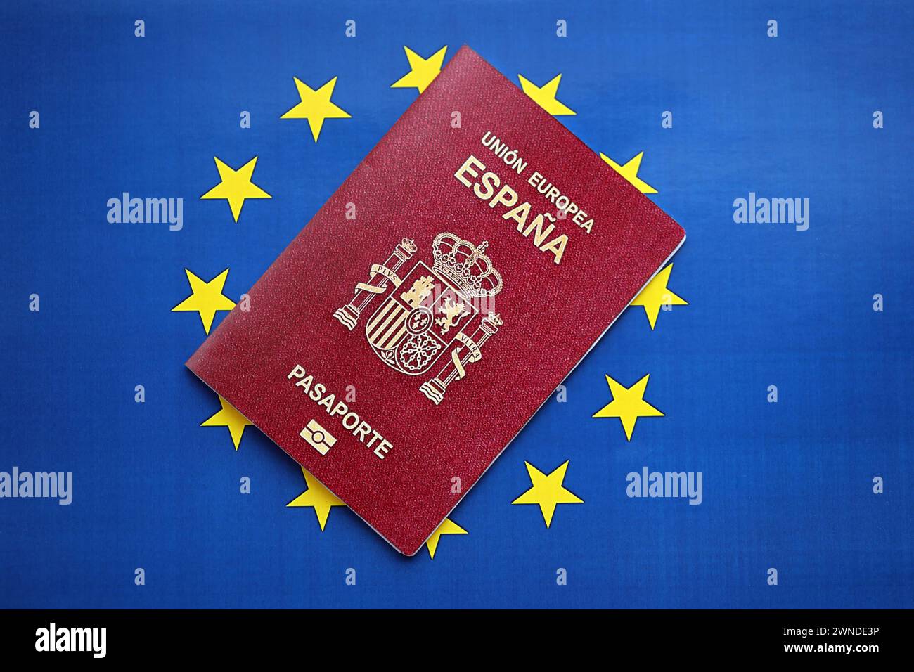 Red Spanish passport of European Union on blue flag background close up ...