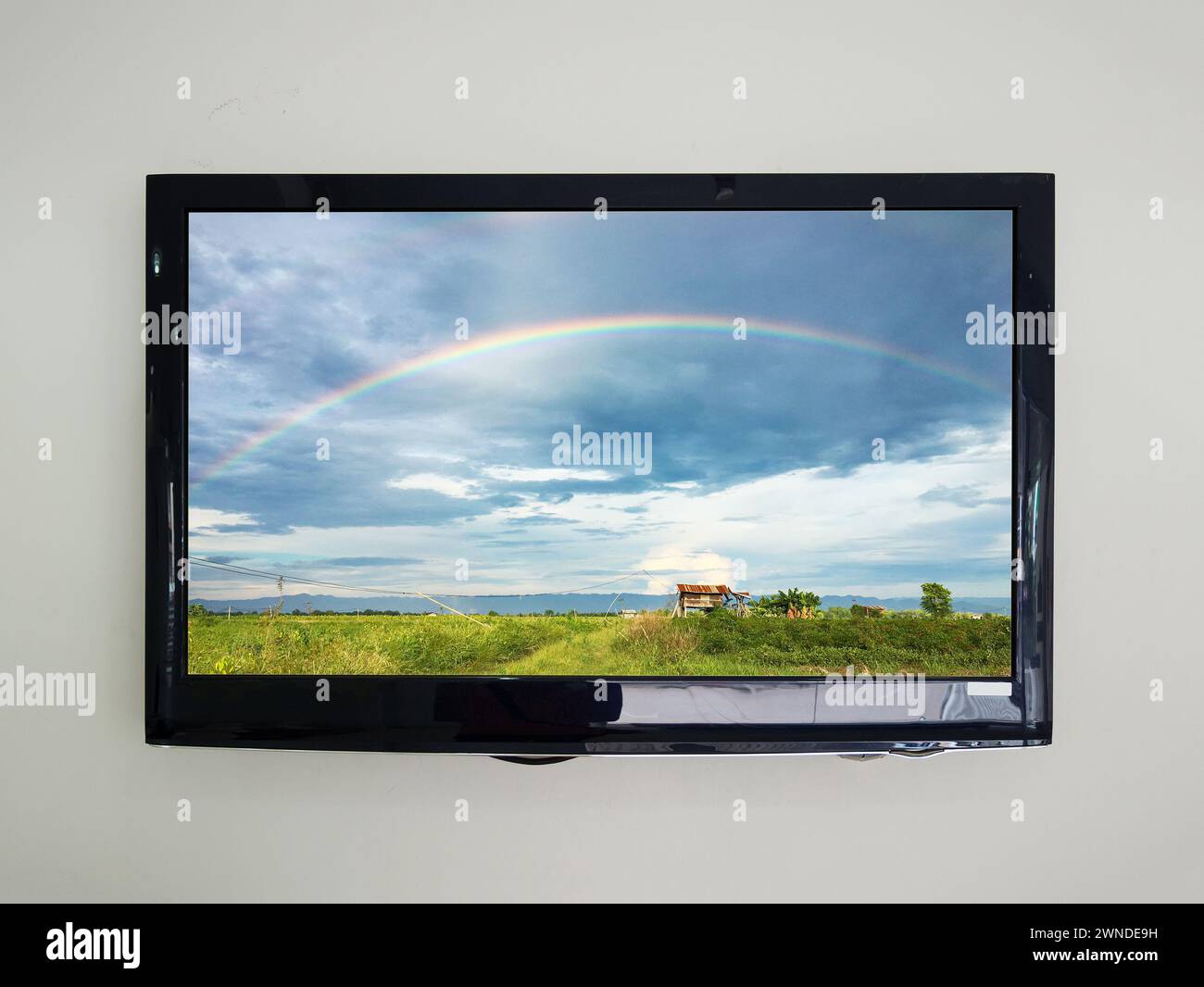 Led tv on the wall background with rainbow in the sky over agriculture ...