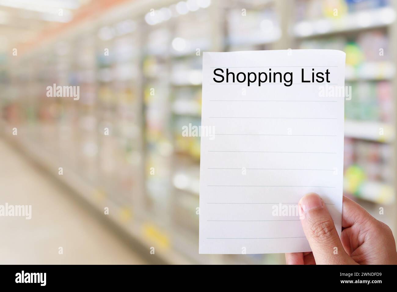 hand hold shopping list paper over supermarket aisle blur background ...