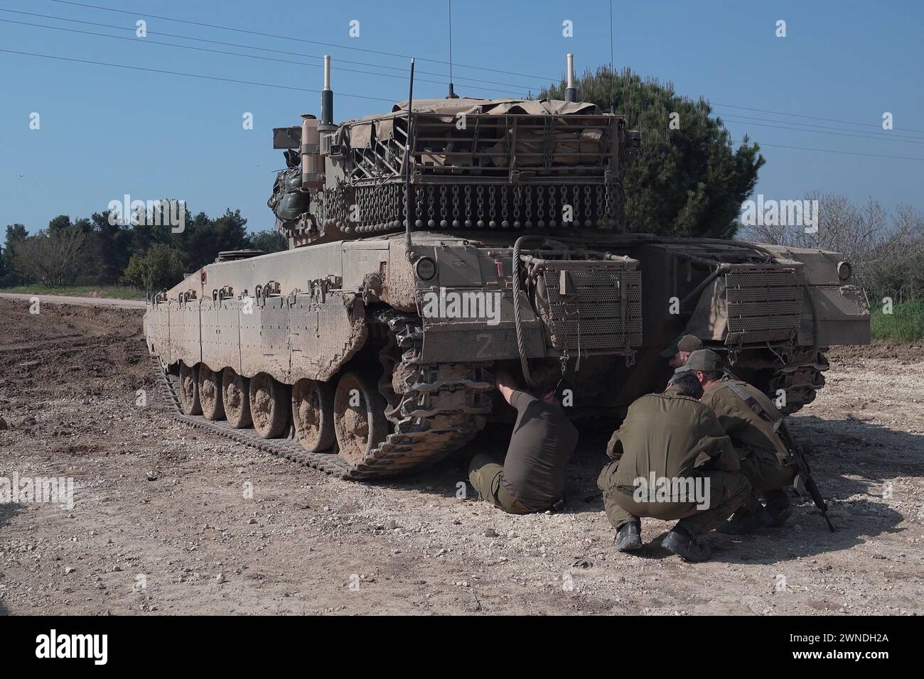 Israeli soldiers repair a tank in a military position near the Gaza ...