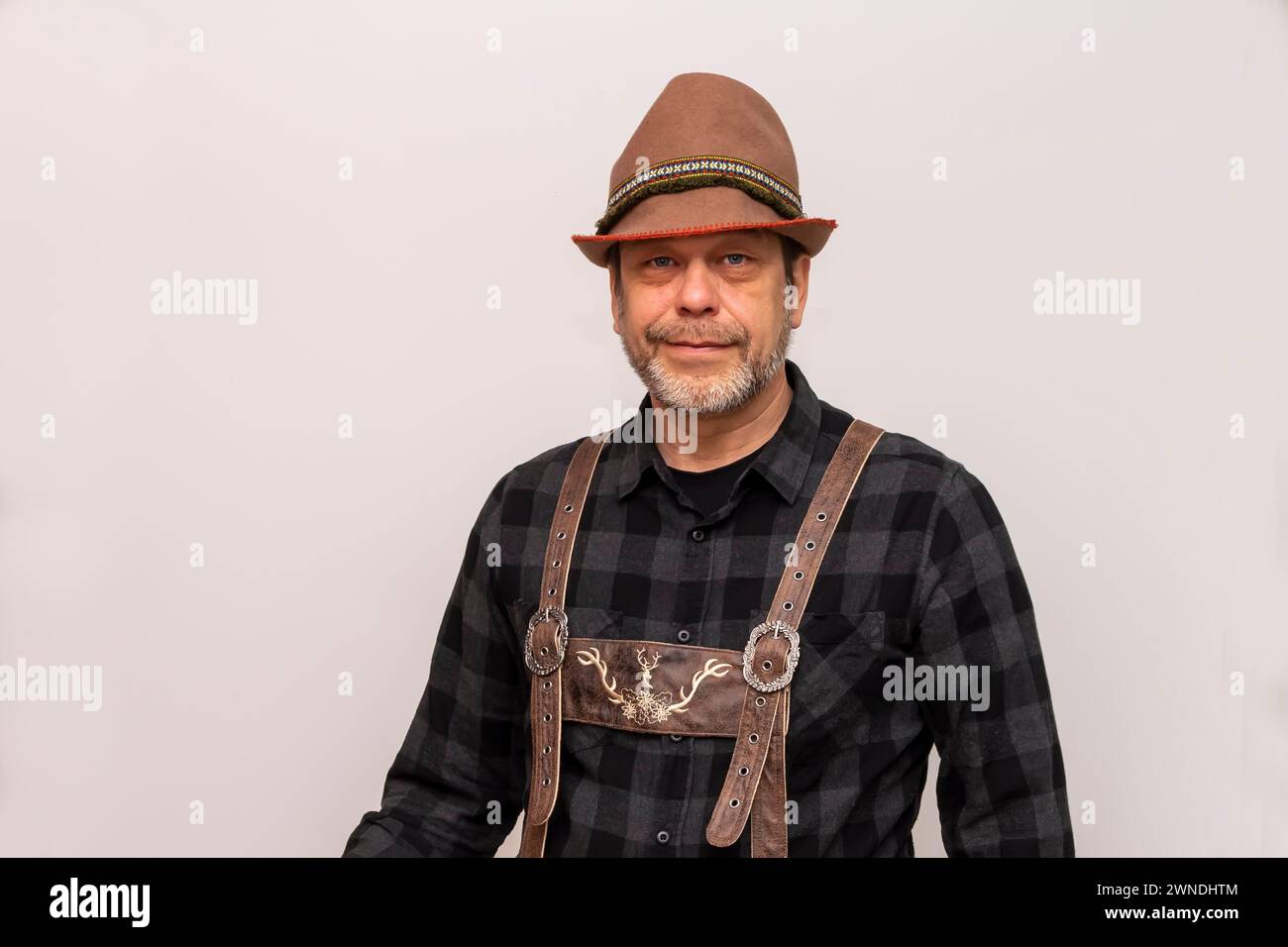 Man in Tyrolean hat with feather and leather shorts on white background ...