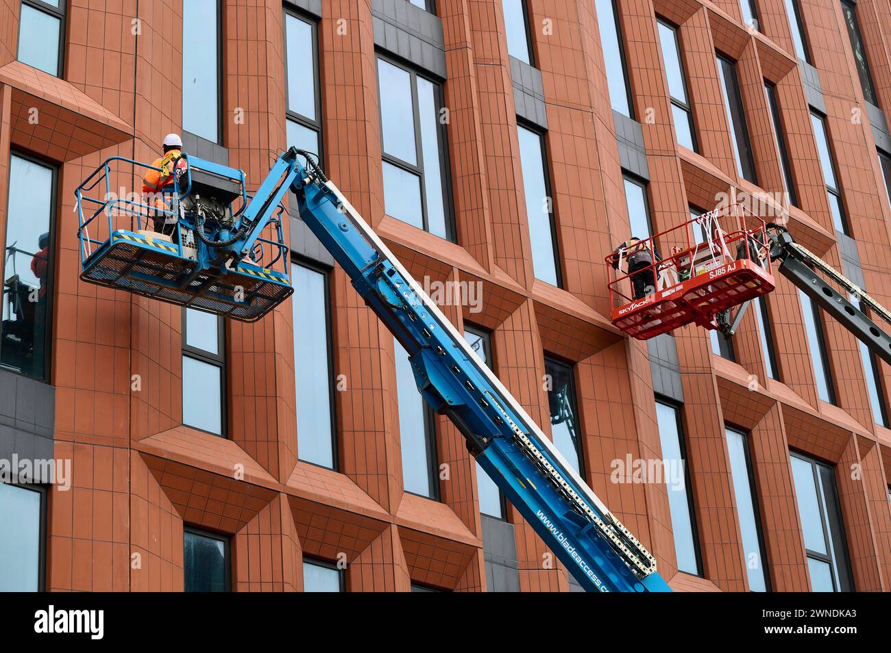 Construction workers on raised platforms putting finishing touches to ...