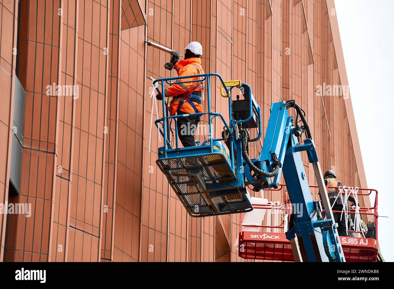 Construction workers on raised platforms putting finishing touches to ...