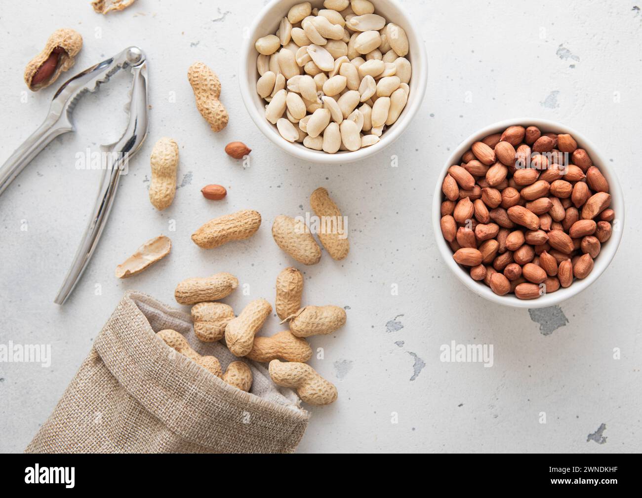 Whole and peeled peanut nuts with cracker and linen bag on light ...