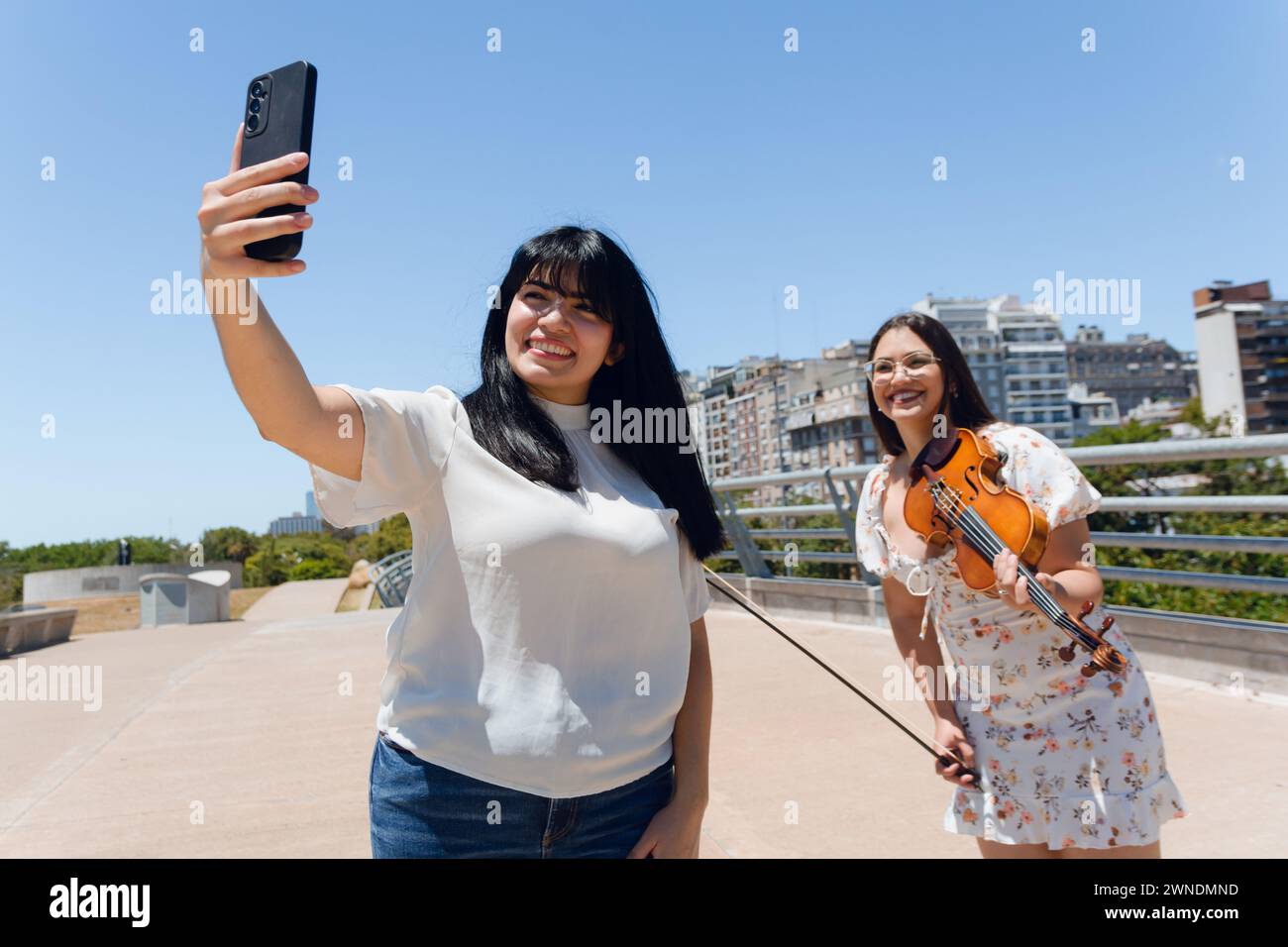 young Venezuelan latin woman outdoors happy standing taking selfie photo with her phone with ...