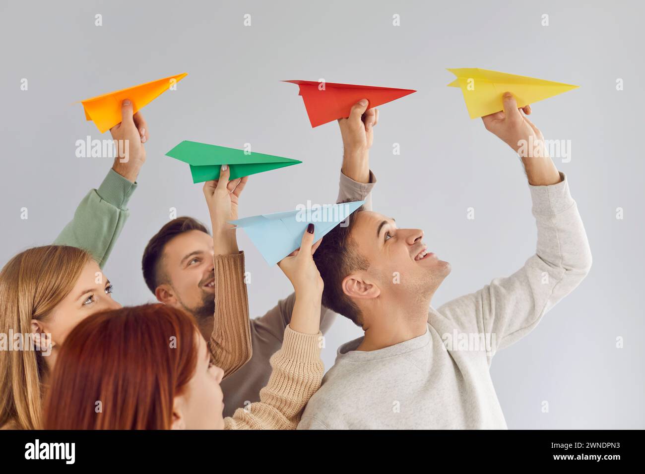 Joyful group of young people enthusiastically launching colorful paper ...
