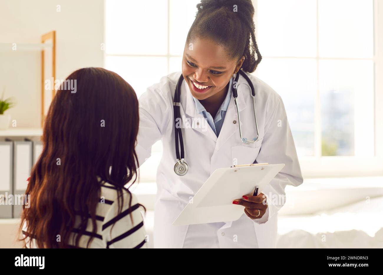 Friendly dark-skinned female doctor discussing treatment with patient ...
