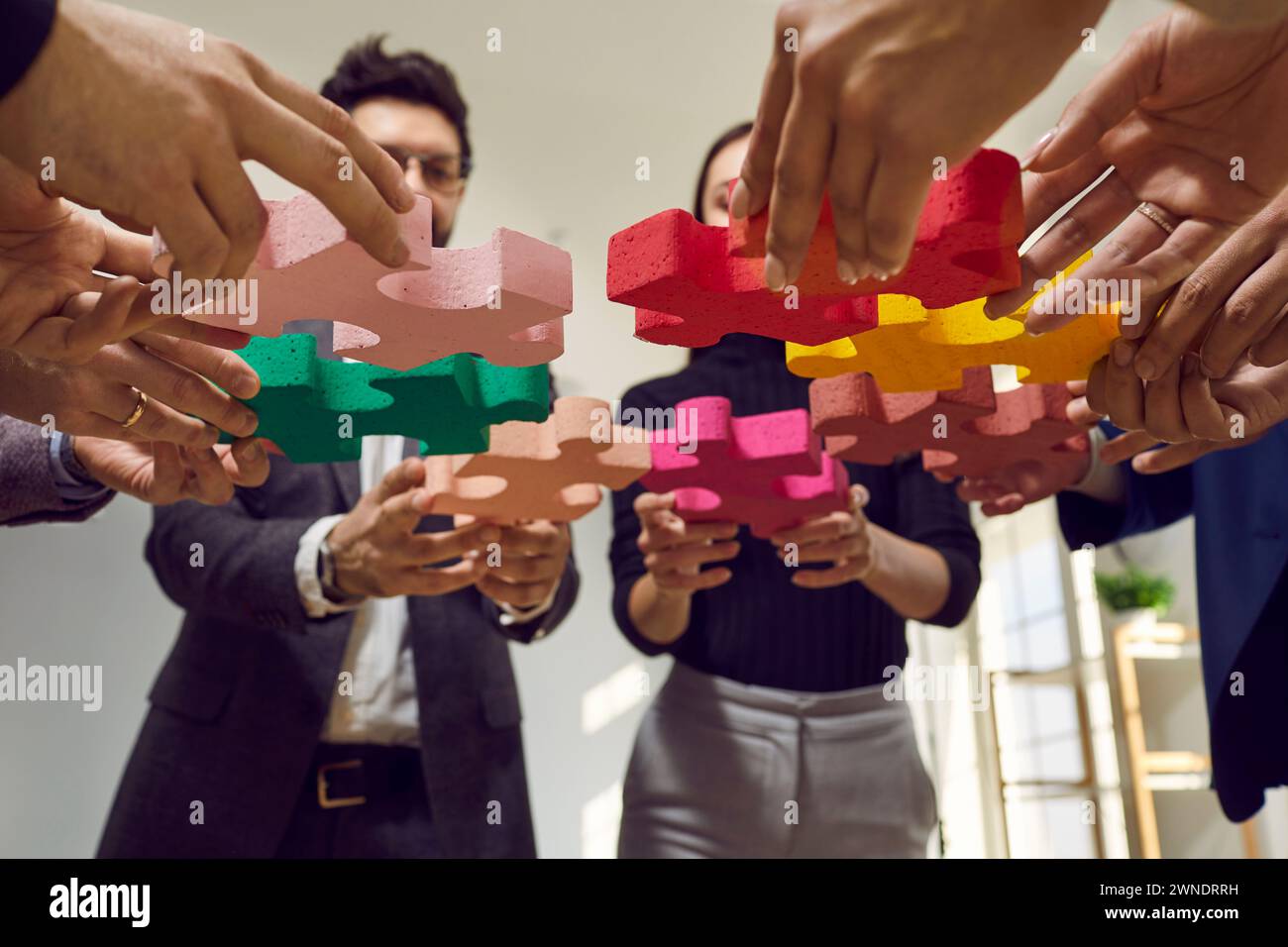 Team of business people joining parts of a jigsaw puzzle to illustrate ...