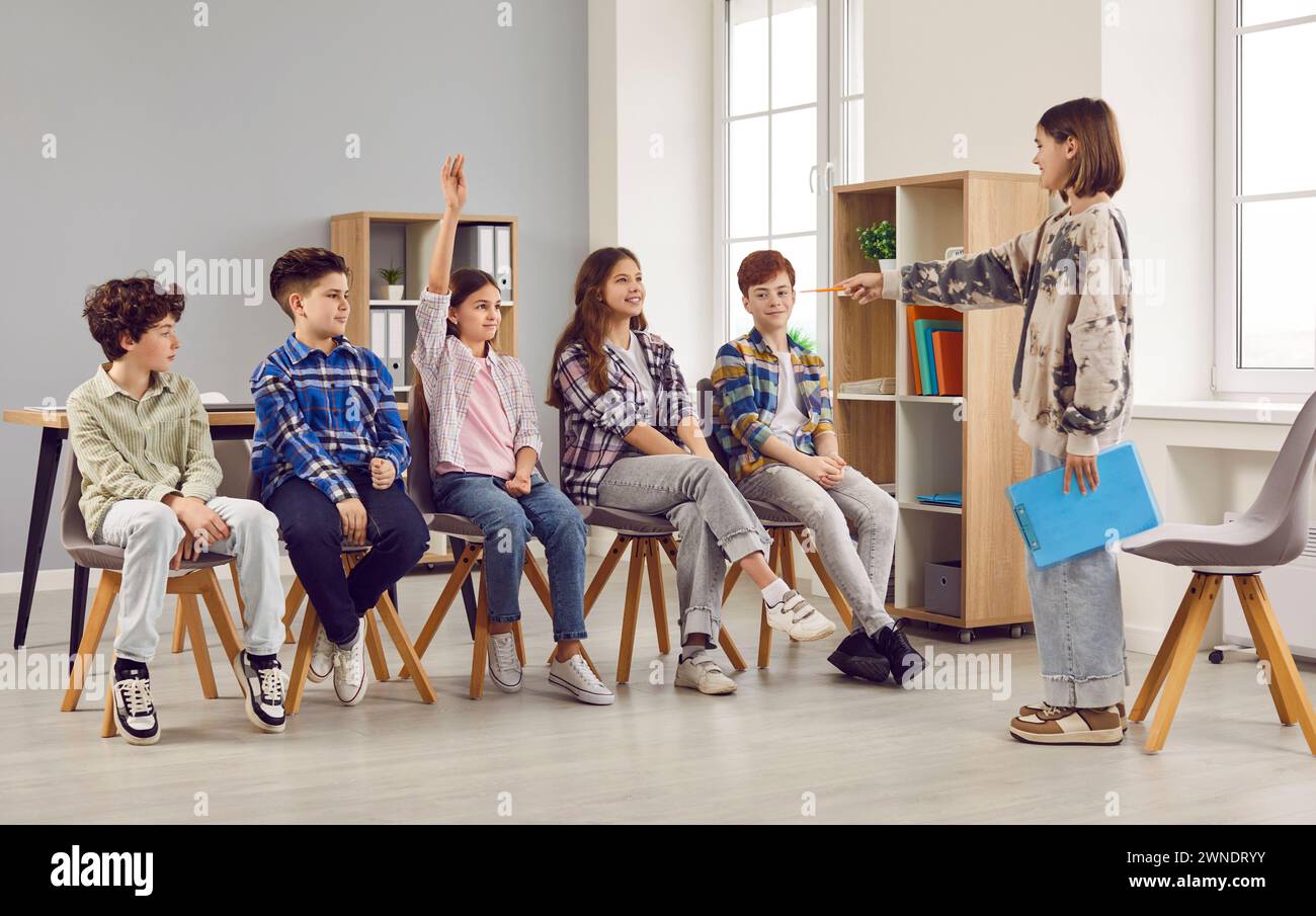 Group of smiling school children in casual wear sitting in row in ...