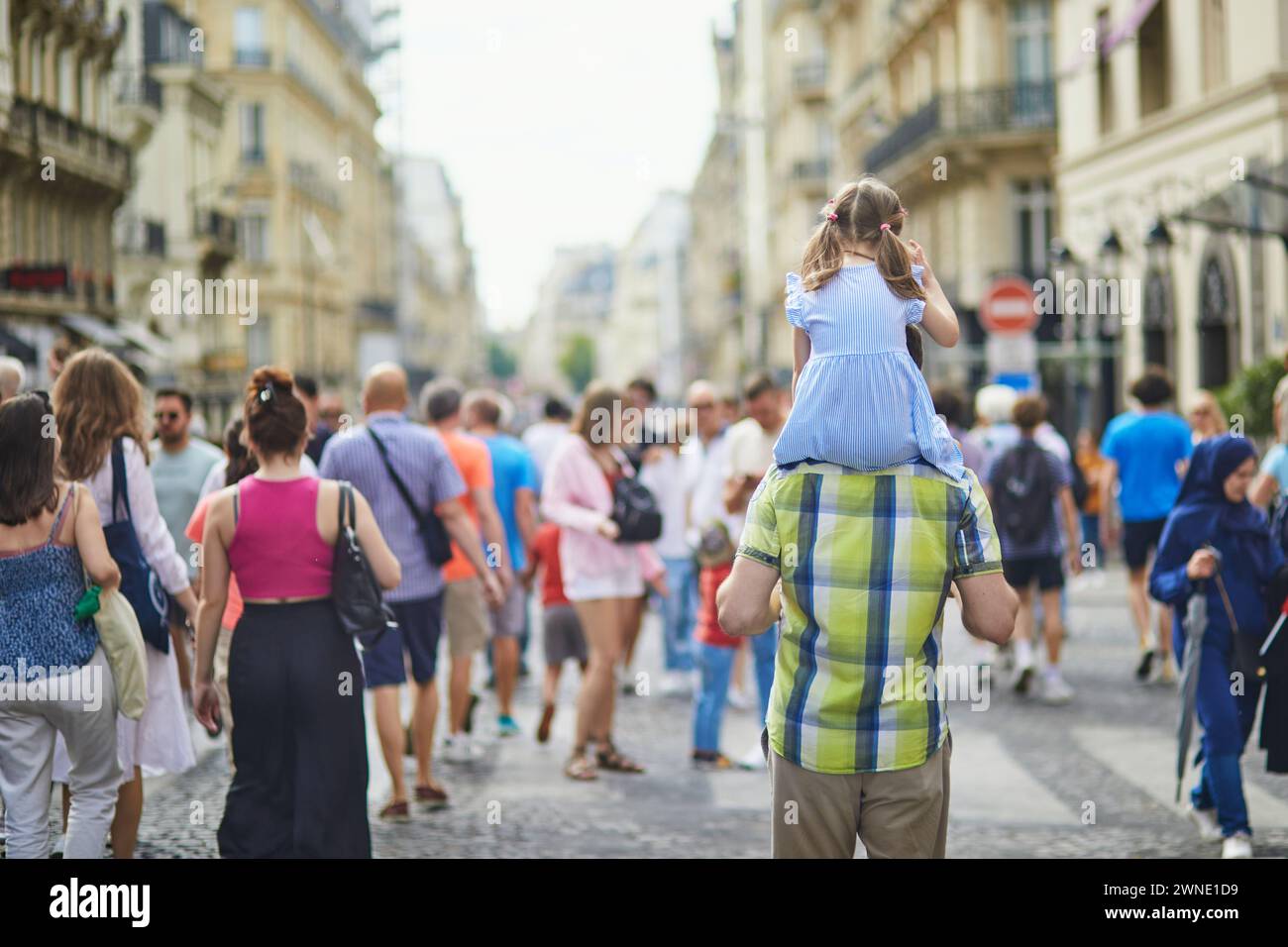 Father holding his daughter on shoulders and walking on a street of ...