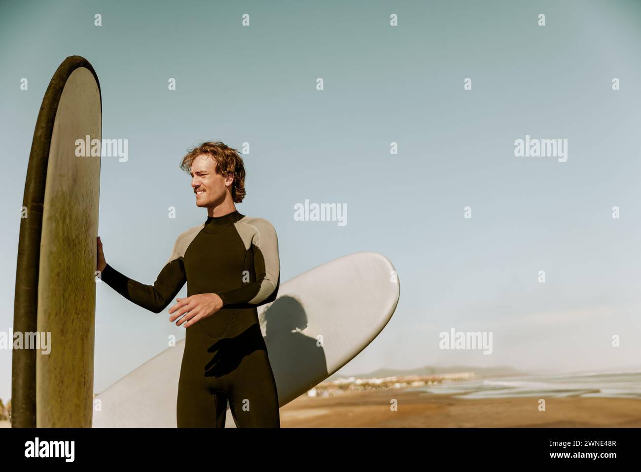 Male surfer in wetsuits standing with surfboard and preparing for ride ...