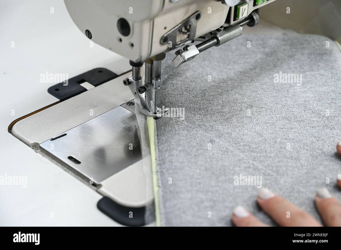 A woman sews a textile with a sewing machine. Female worker works in ...
