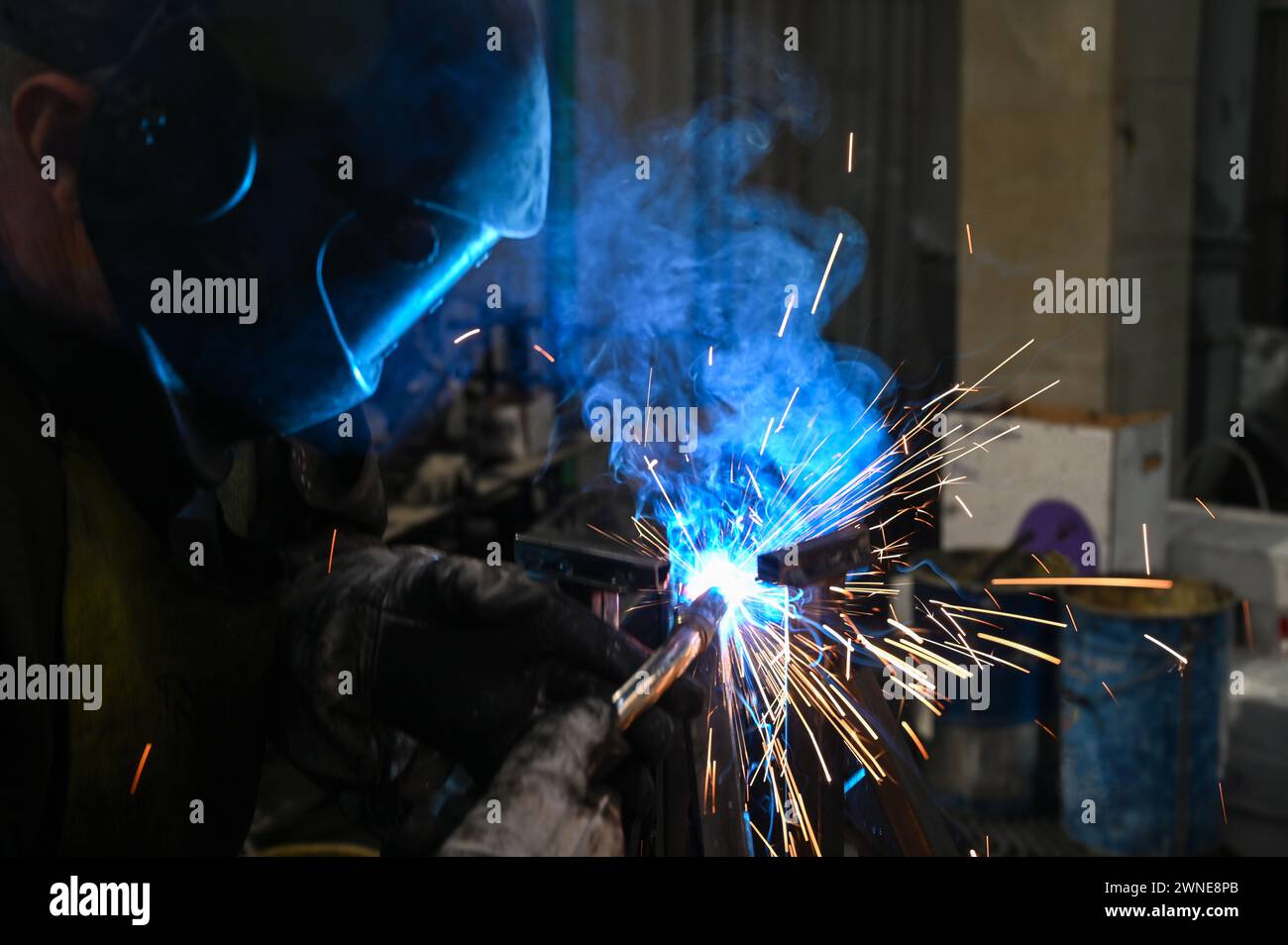 Welder at work. Welding sparkles. Male worker wearing helmet and gloves ...