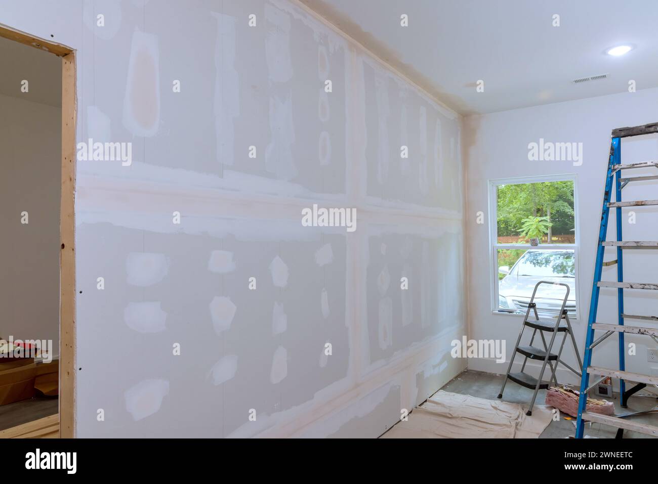 Finishing plastering drywall in ready for paint with newly constructed ...
