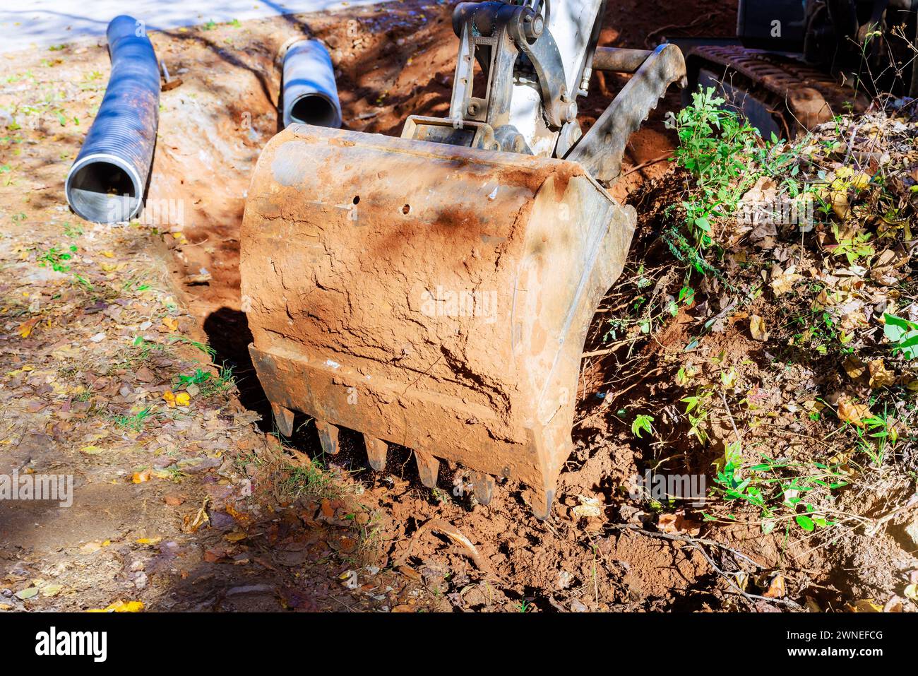 An excavator digs trench for laying pipe through which rainwater will ...