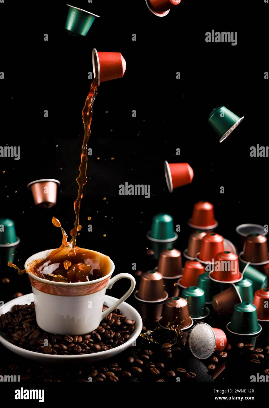 Coffee flows from a floating capsule into a cup, surrounded by capsules ...