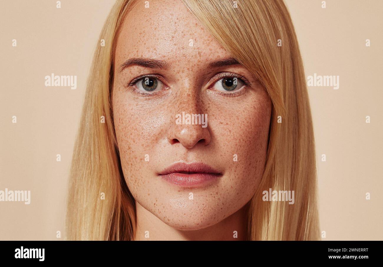 Close-up studio portrait of a blond female with freckles. Cropped shot ...