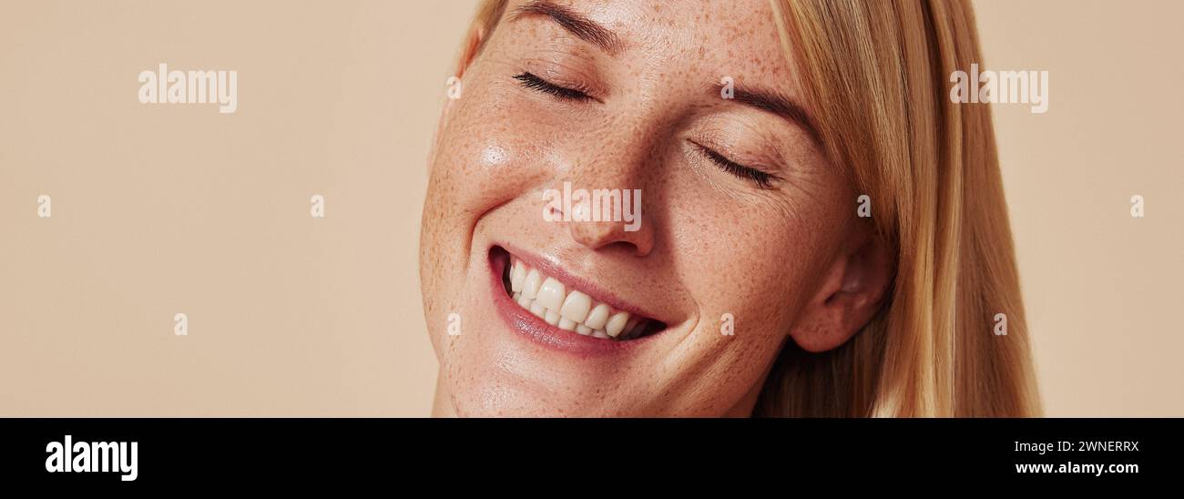 Portrait of a young happy woman tilting her head on the side. Close-up studio shot of happy ...