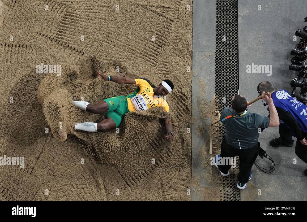 Jamaica's Carey Mcleod lands in the pit as staff rake the sand during ...