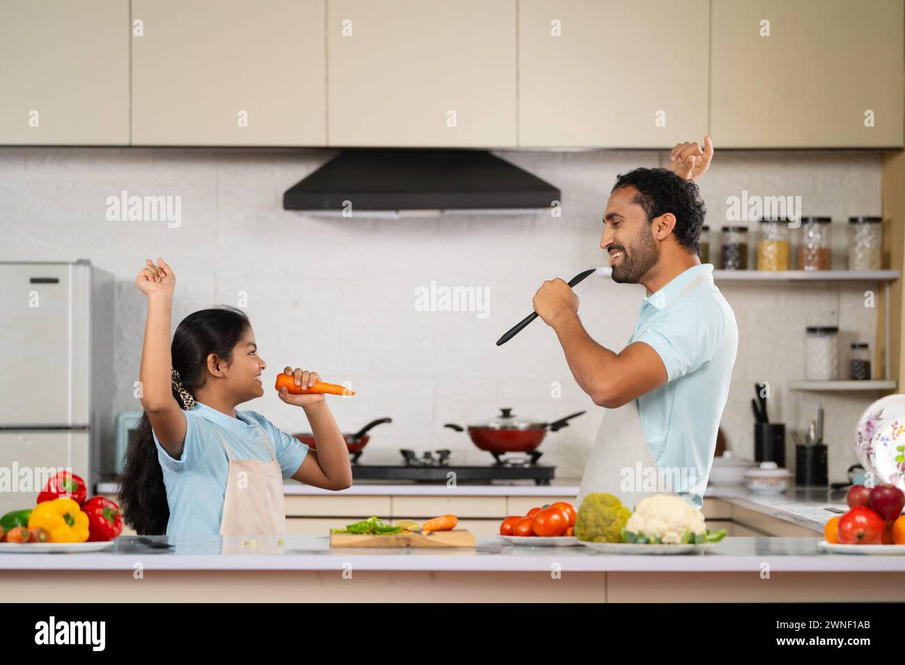 Joyful Indian father with kid dancing together at kitchen while cooking ...