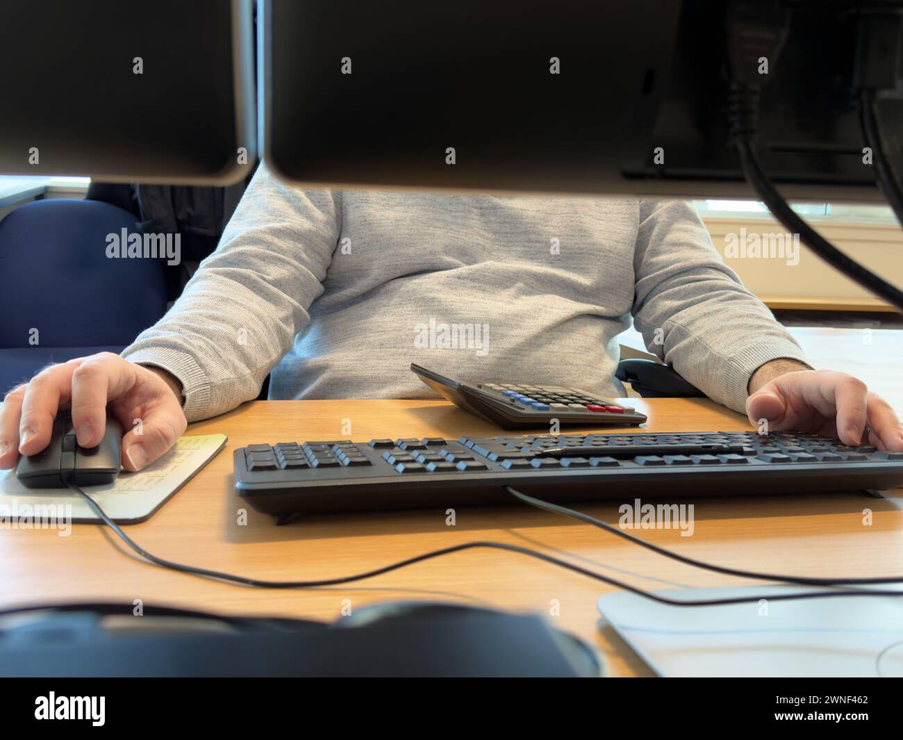 Office worker using computer at desk Stock Photo - Alamy