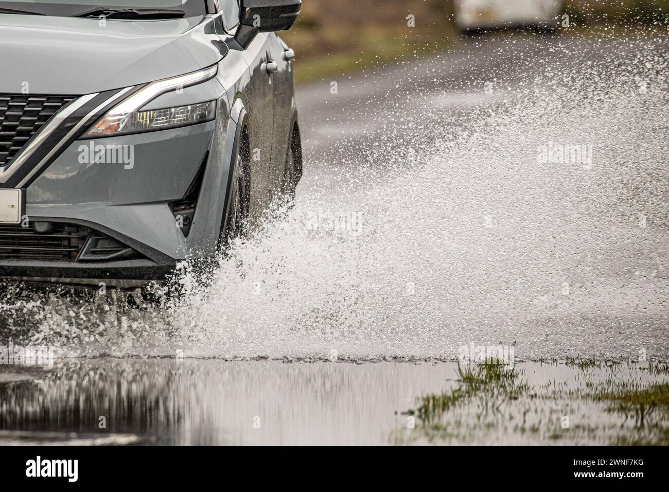 Water spray from a car wheel and the front section of the car as it ...